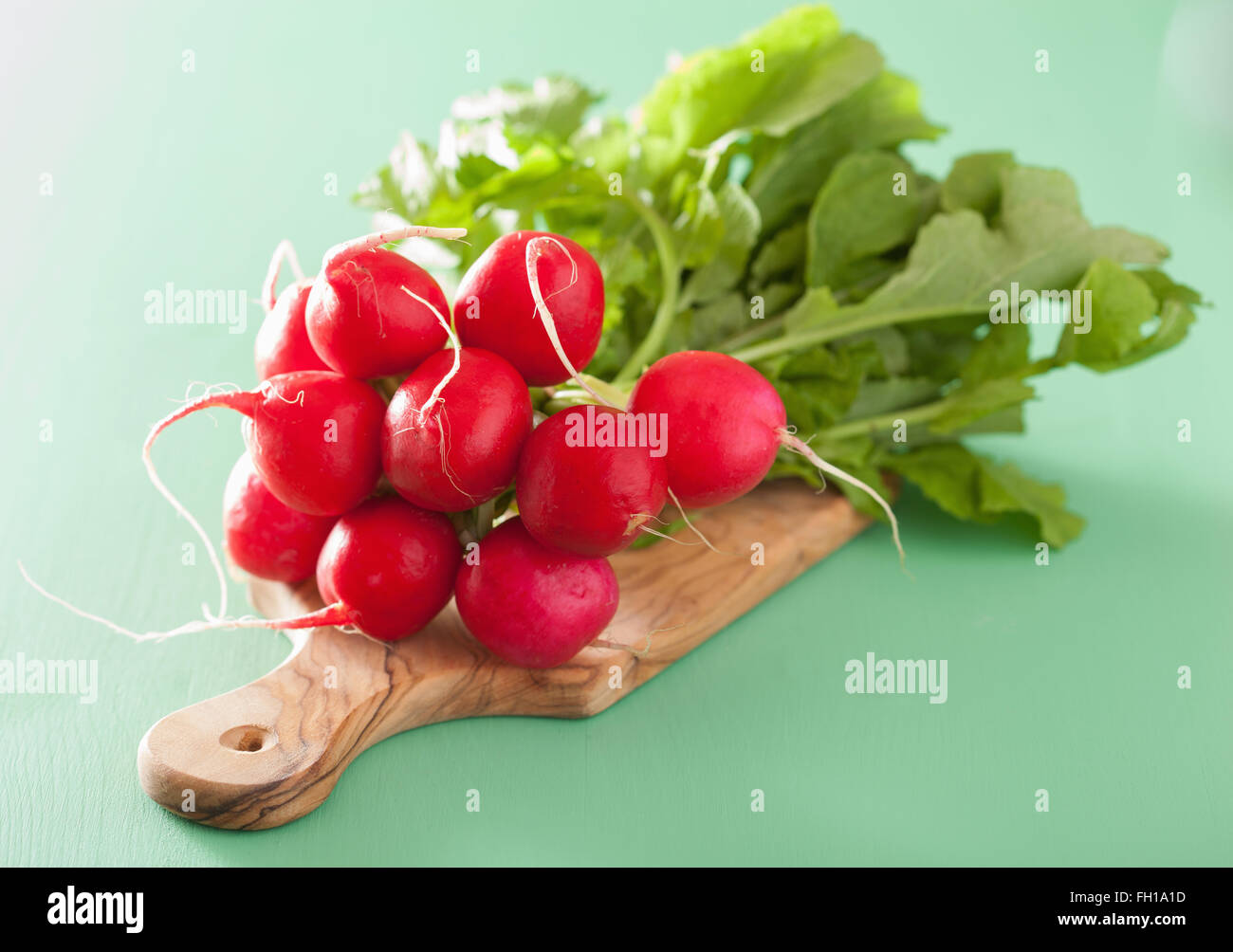 fresh radish with leaves over green background Stock Photo - Alamy