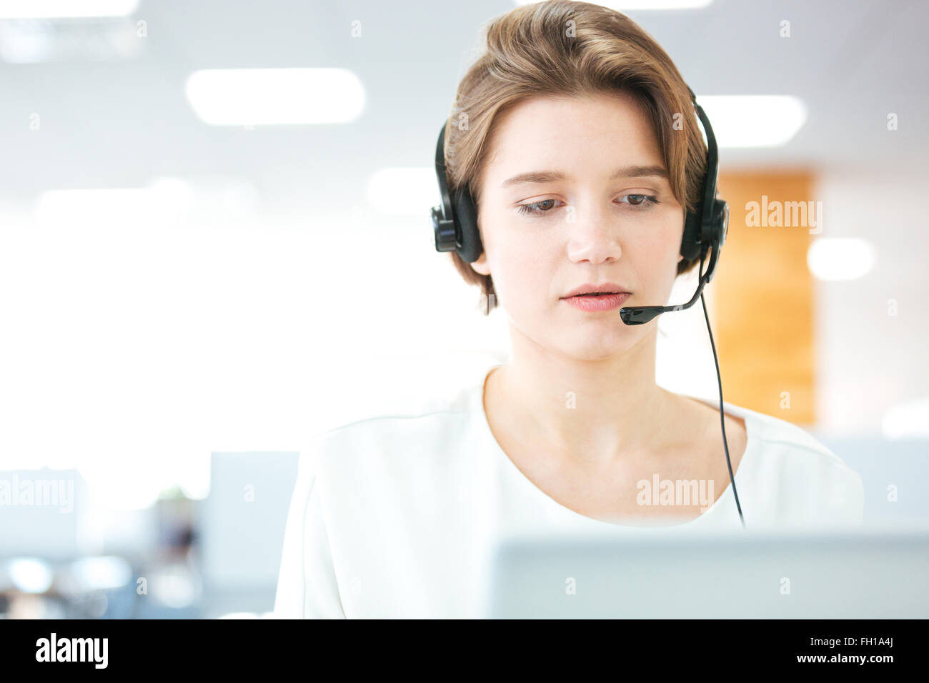 Serious pretty young woman working as support phone operator with ...