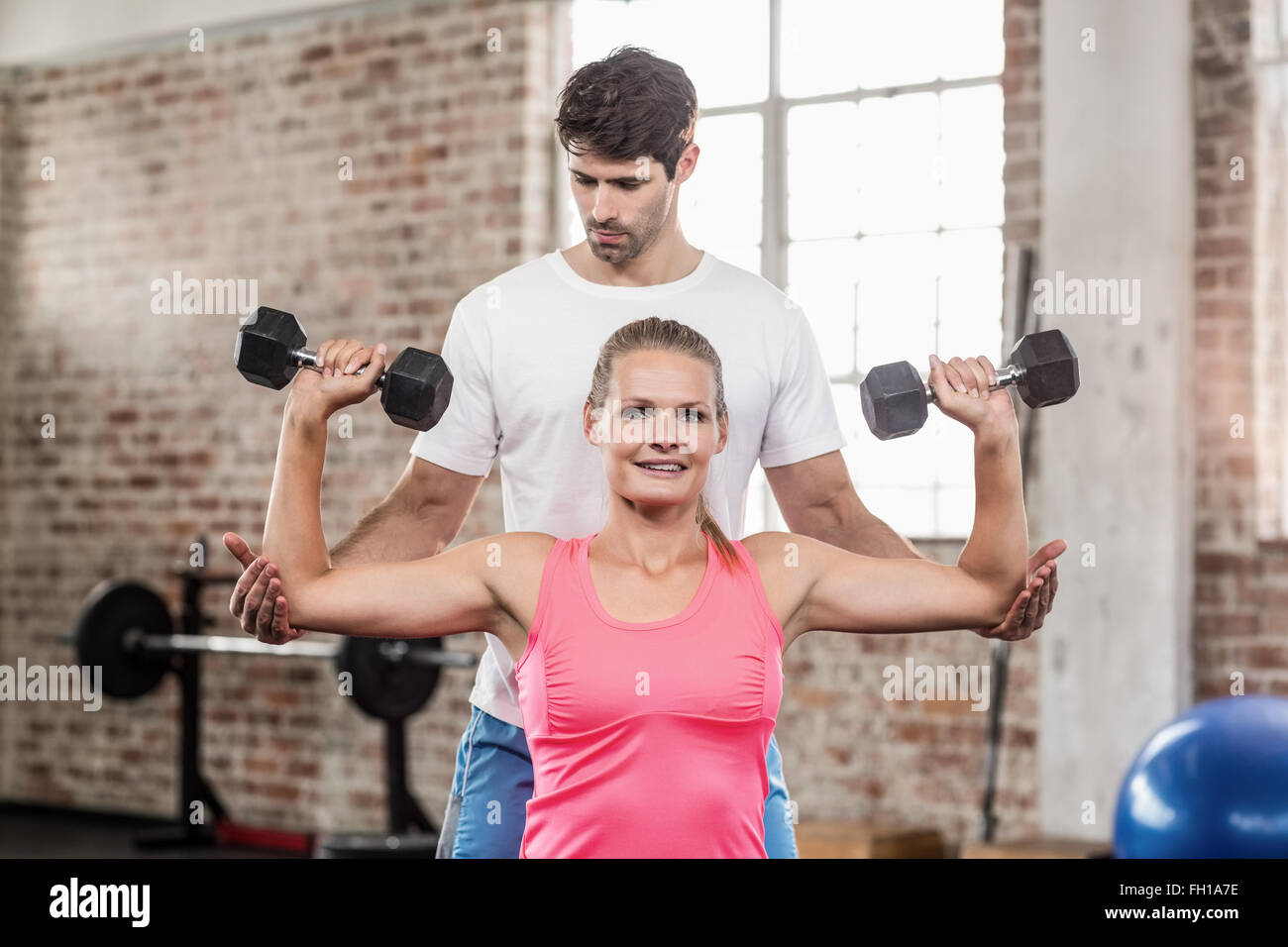 Fit woman lifting dumbbells with trainer Stock Photo - Alamy