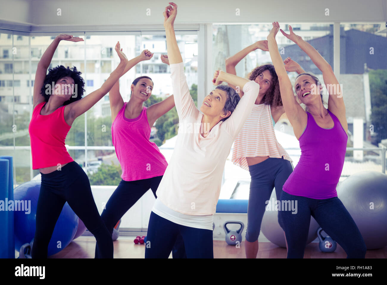 Happy women exercising with arms raised while looking up Stock Photo ...