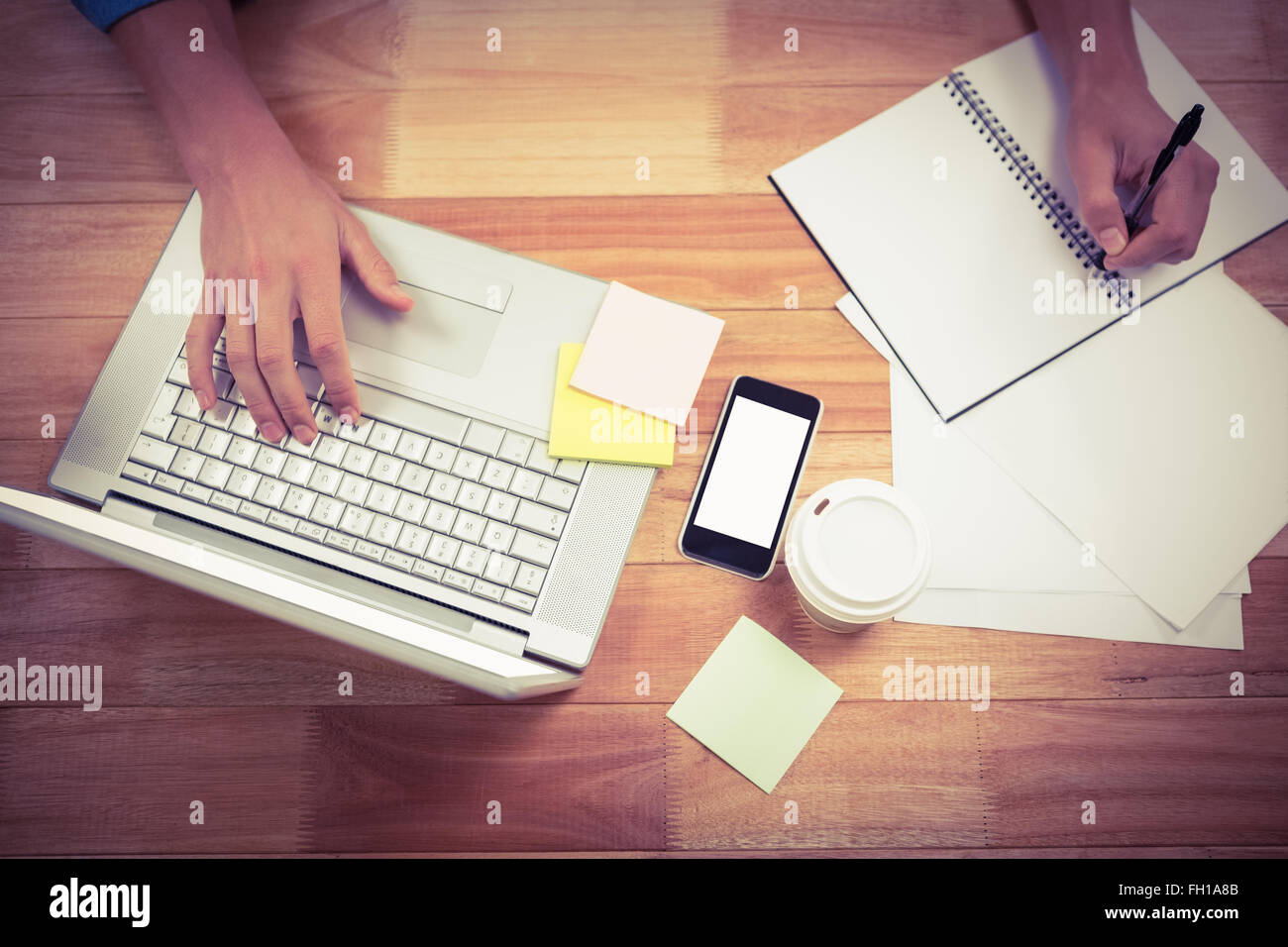 Businessman writing on spiral book using laptop Stock Photo - Alamy