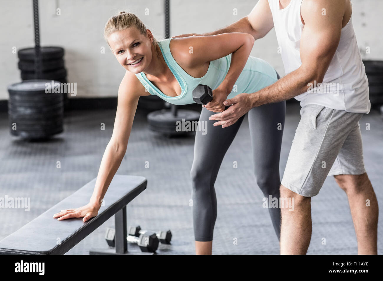 Personal trainer helping client lift dumbbells Stock Photo - Alamy
