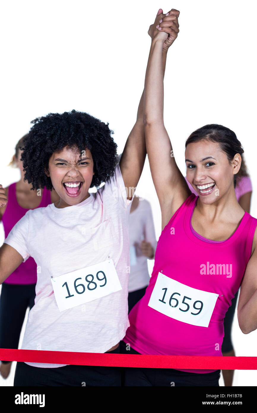 Portrait of cheerful winner athletes crossing finish line with arms ...