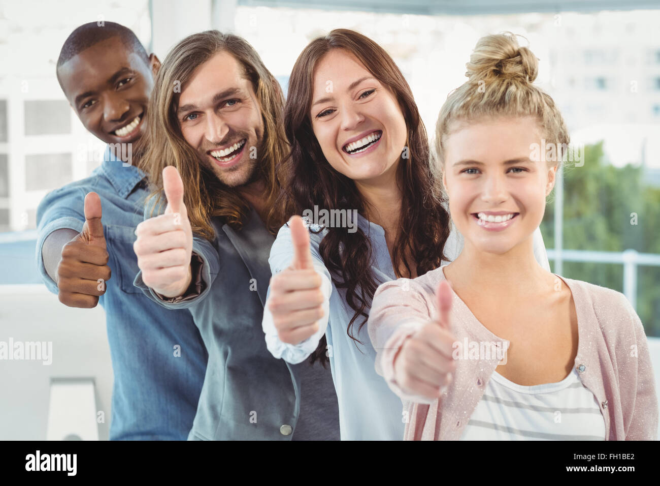 Portrait of happy business team with thumbs up while standing in row ...