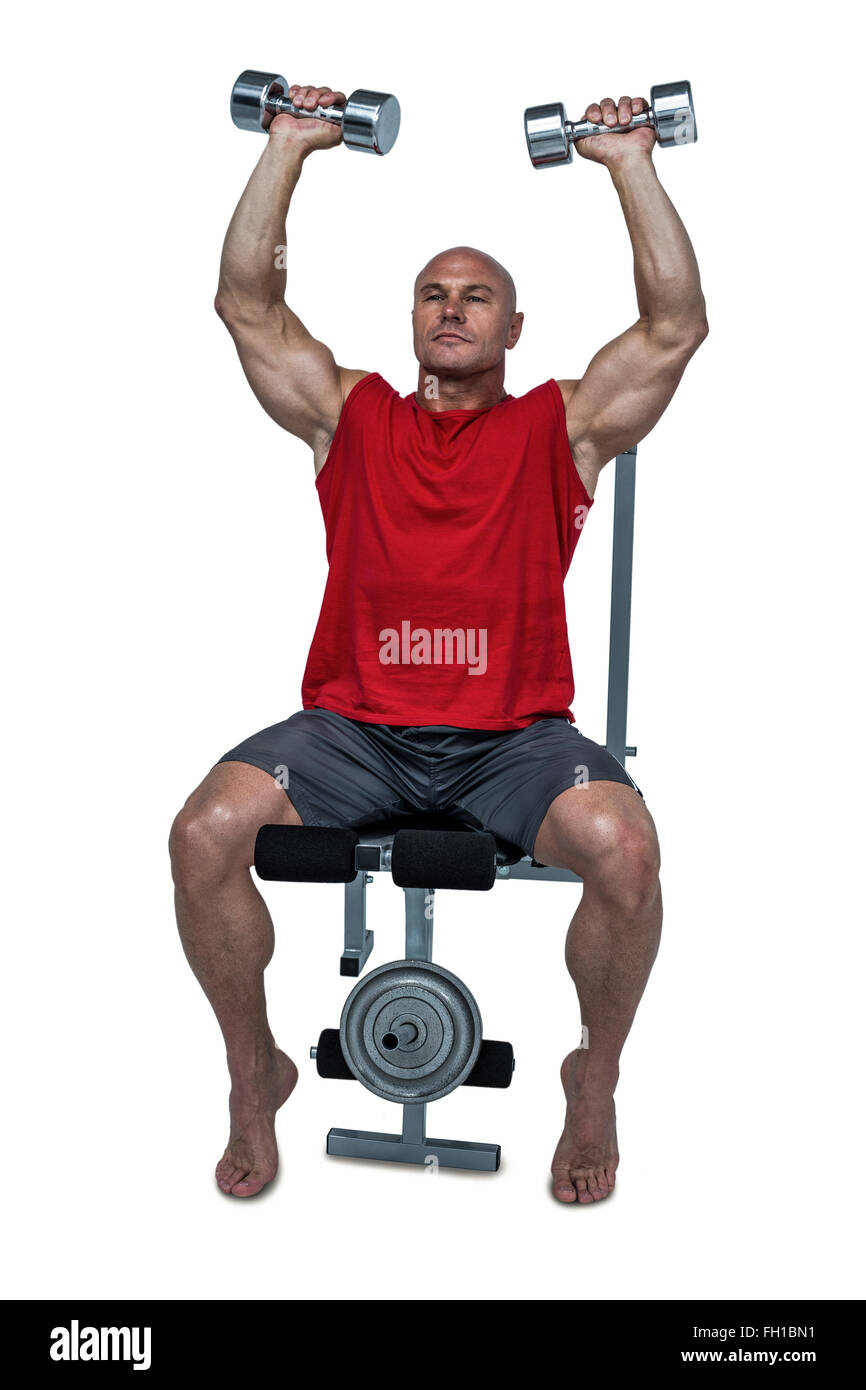 Muscular man exercising while sitting on bench press Stock Photo - Alamy