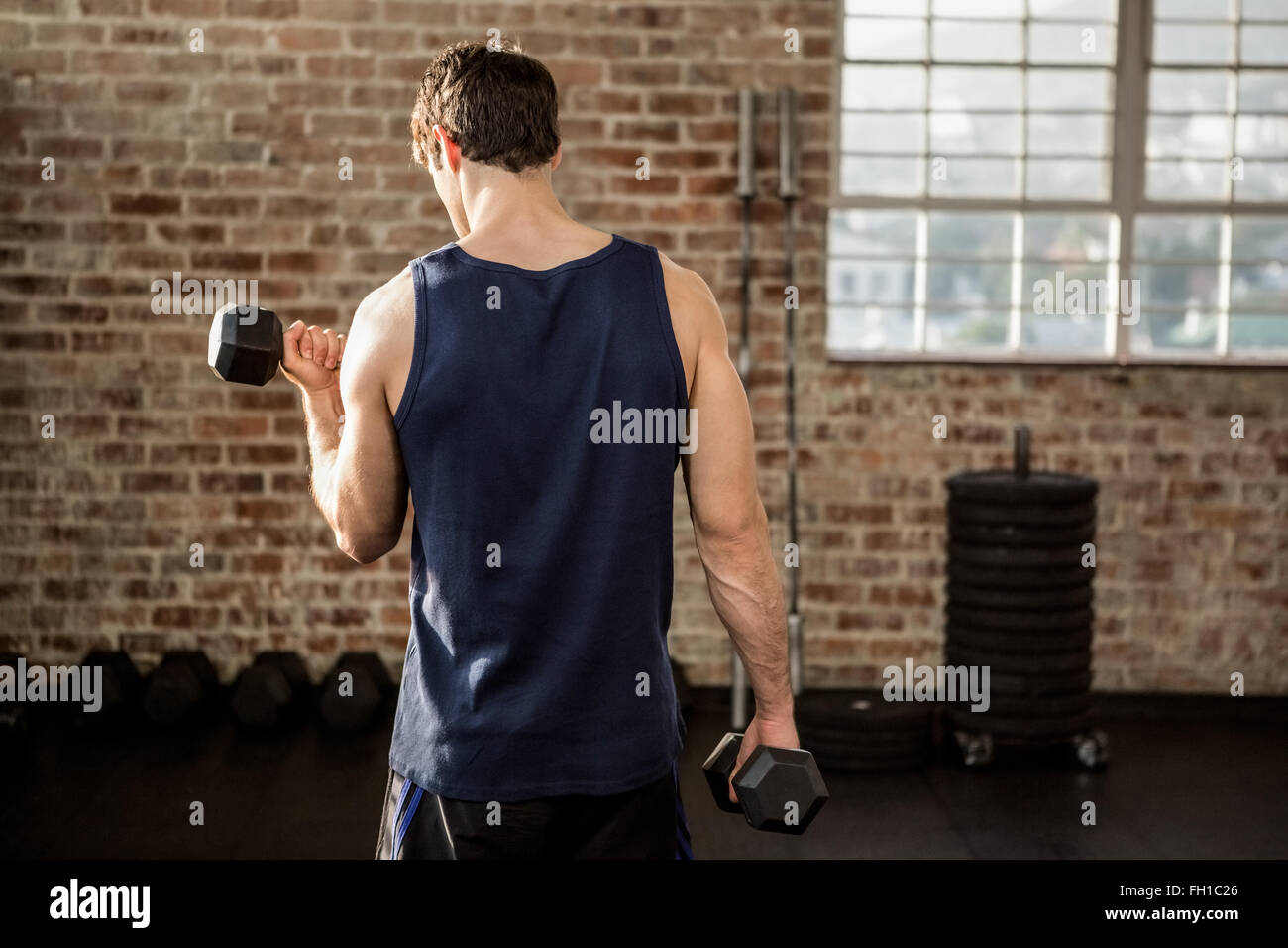 Rear view of man lifting dumbbells Stock Photo - Alamy