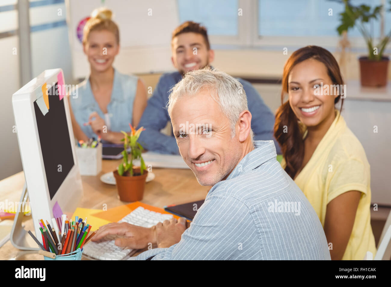 Business people sitting by desk with computer Stock Photo - Alamy