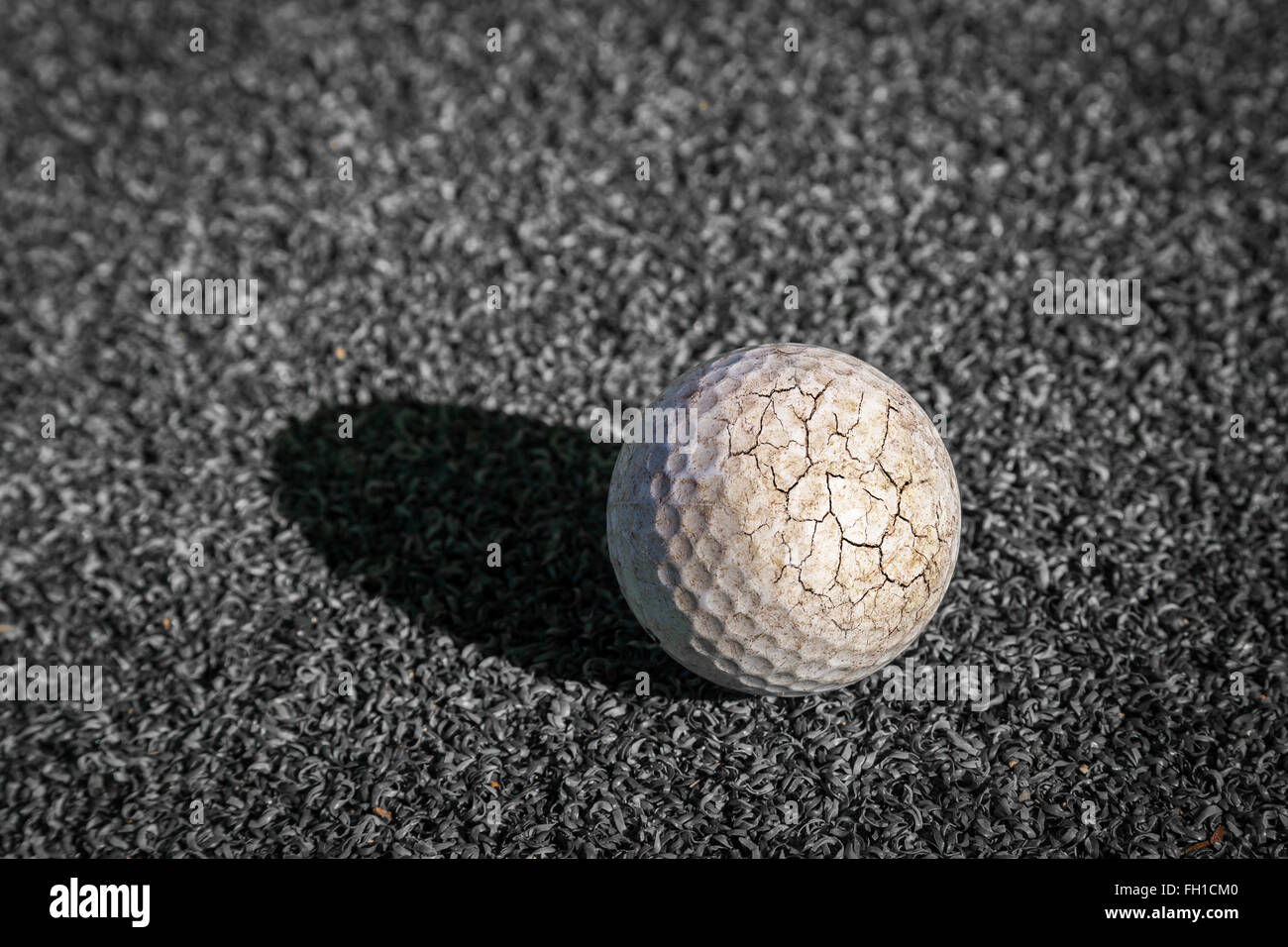 Crack golf ball with sunlight and shadow put on putting green in no ...