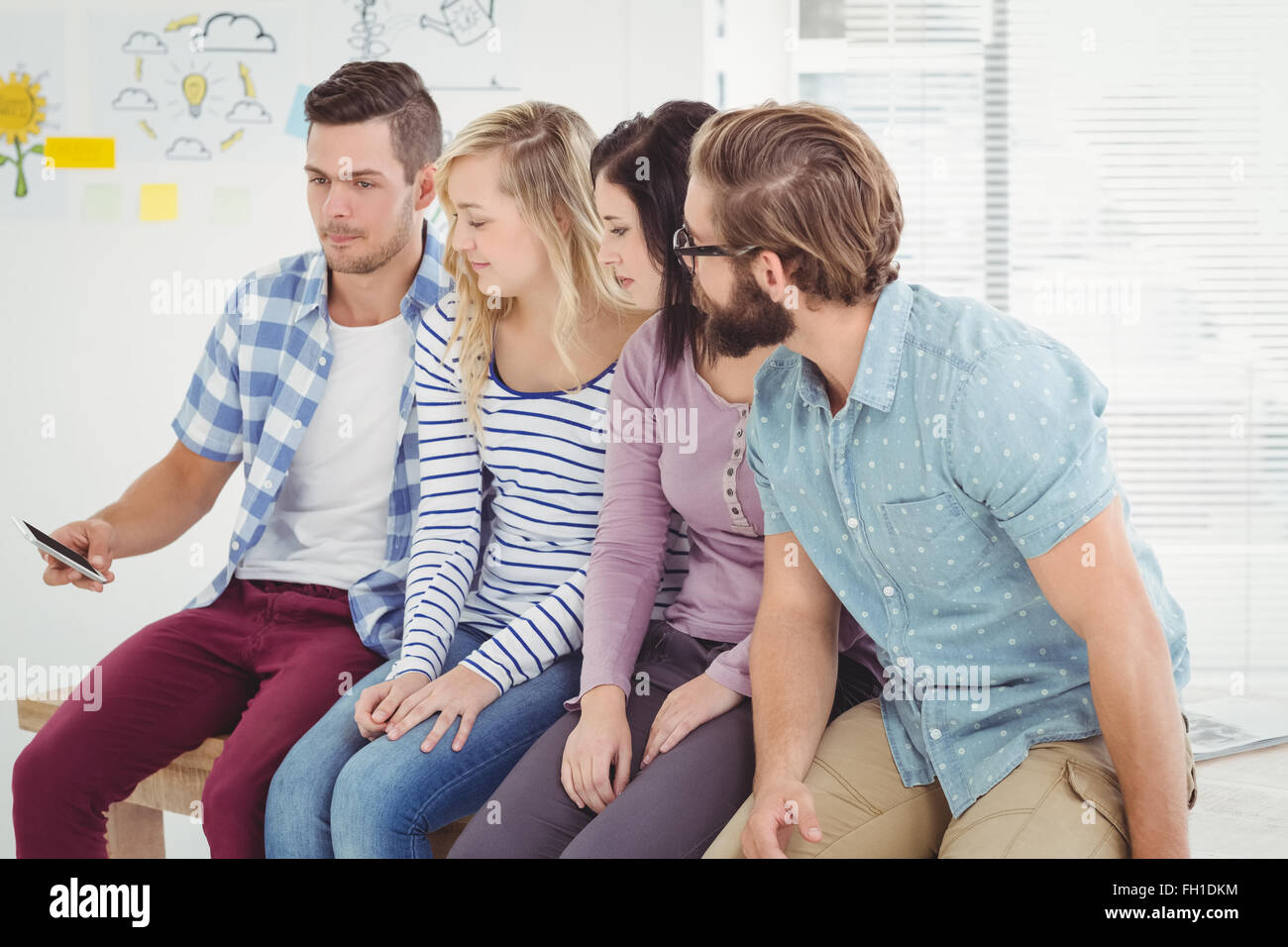 Man holding mobile phone while sitting at desk with coworkers Stock ...