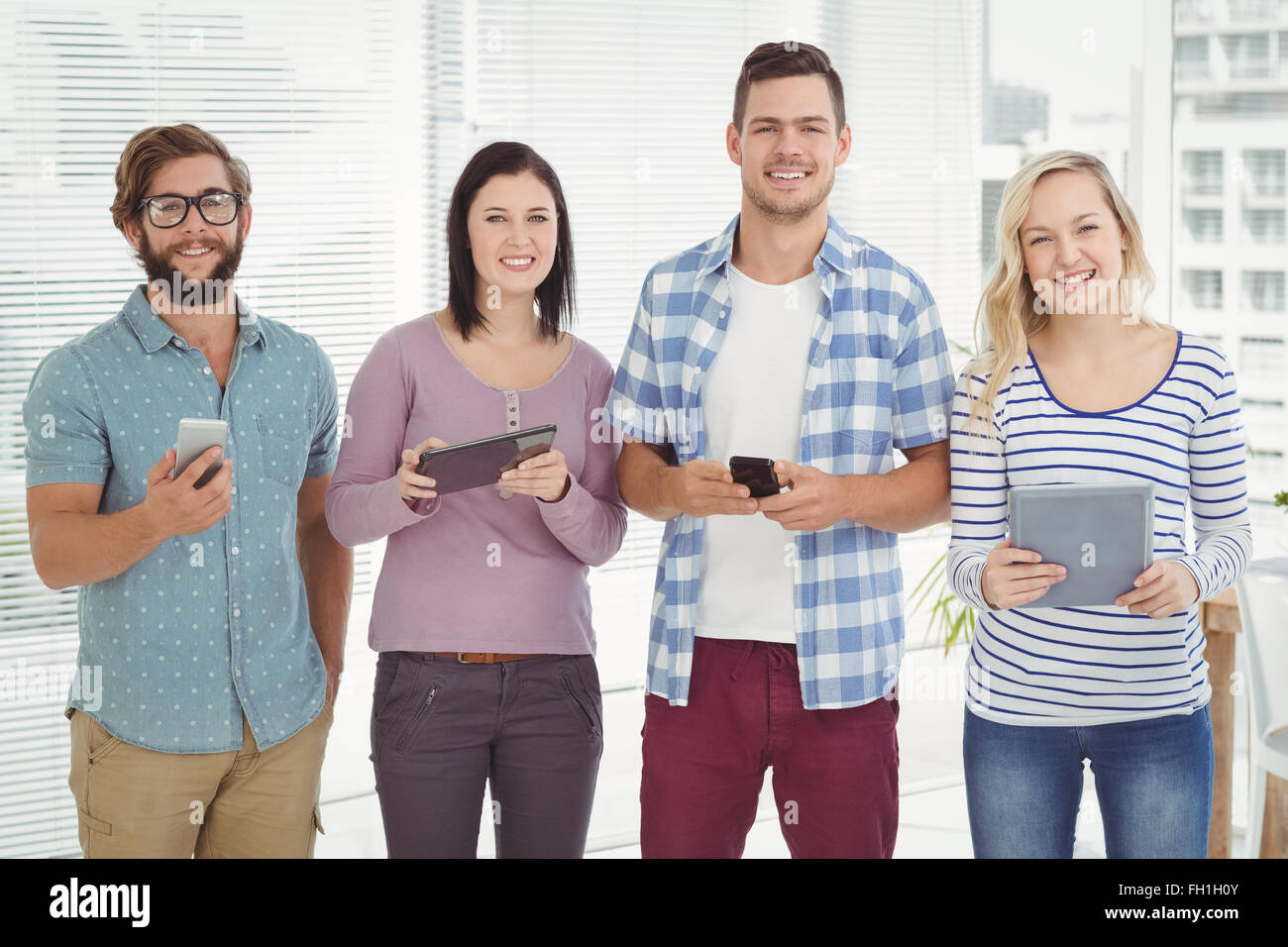 Portrait of smiling business people using electronic gadgets Stock ...