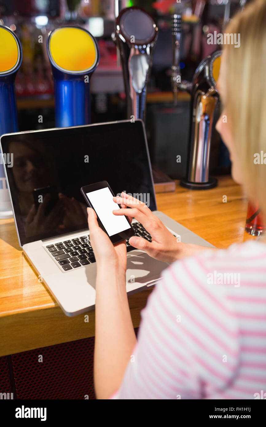 Woman with laptop using mobile phone at table Stock Photo - Alamy