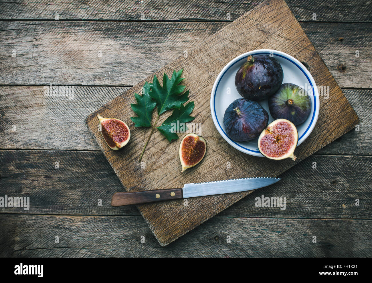 Cut Figs and knife on chopping board in rustic style. Autumn season ...