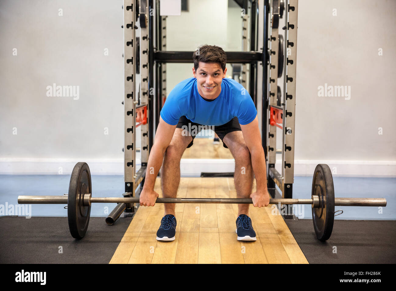 Smiling man about to lift a barbell Stock Photo - Alamy