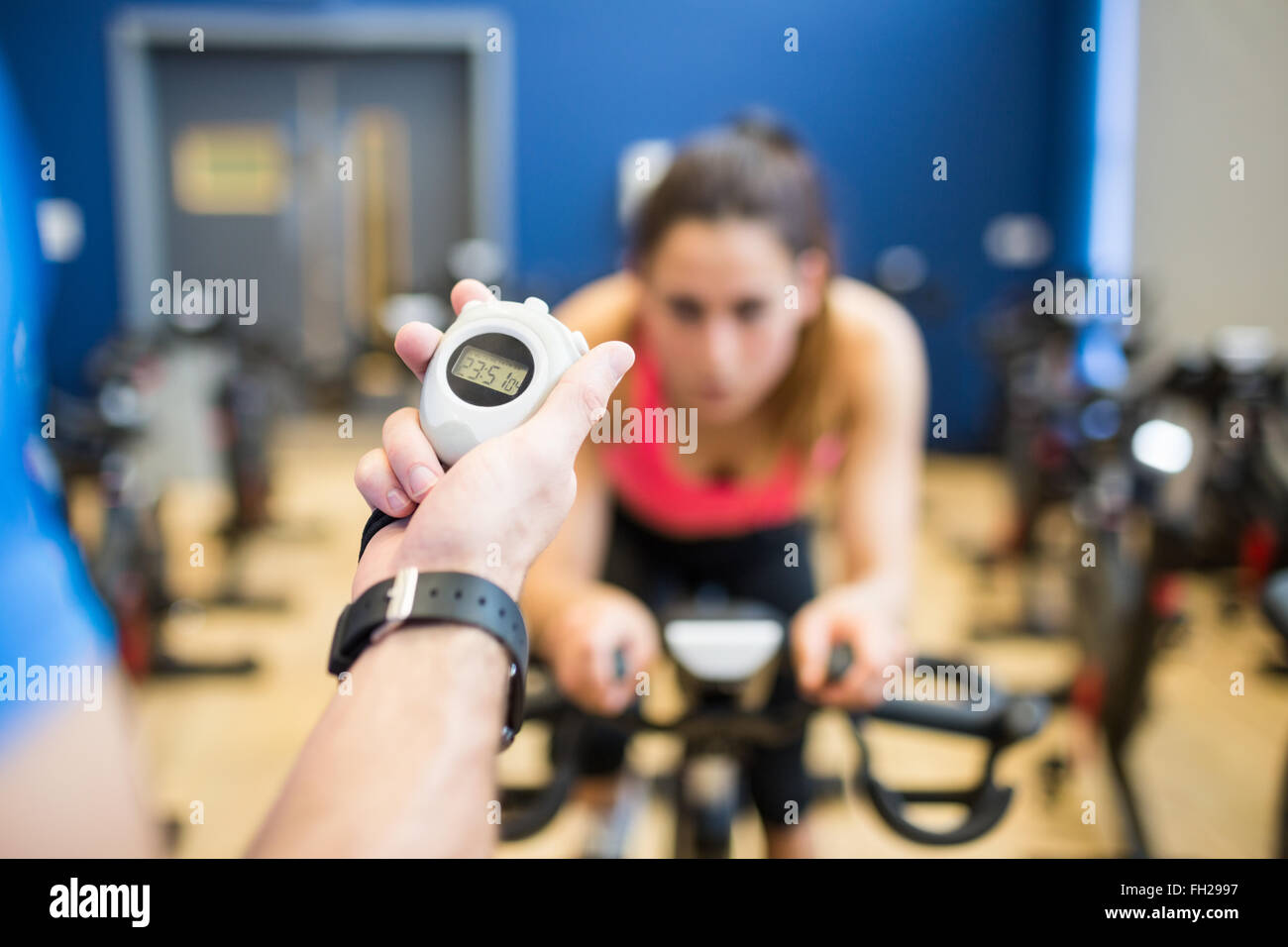 Woman on exercise bike with trainer timing her Stock Photo - Alamy