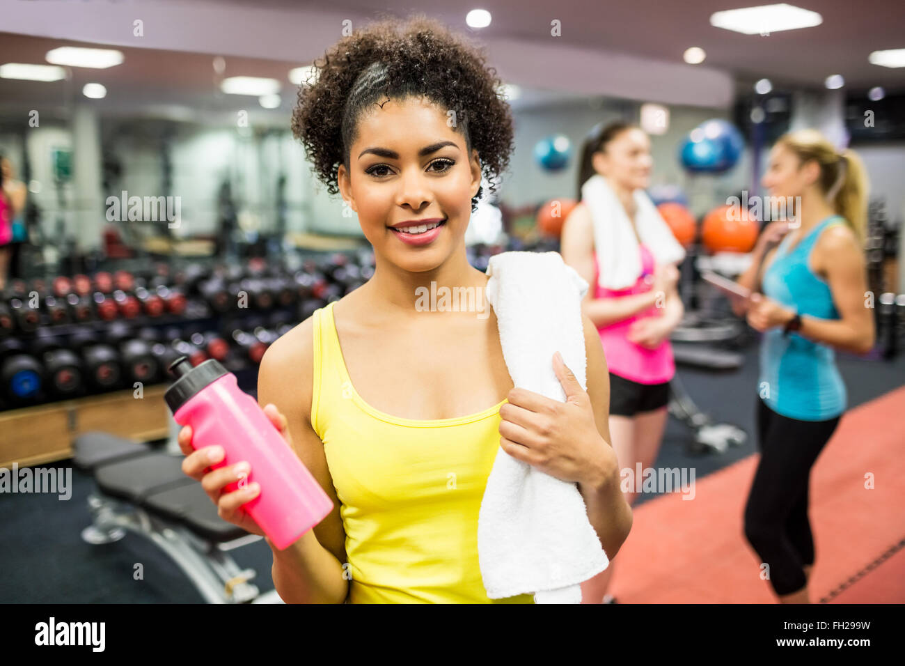 Fit woman smiling at camera in weights room Stock Photo - Alamy