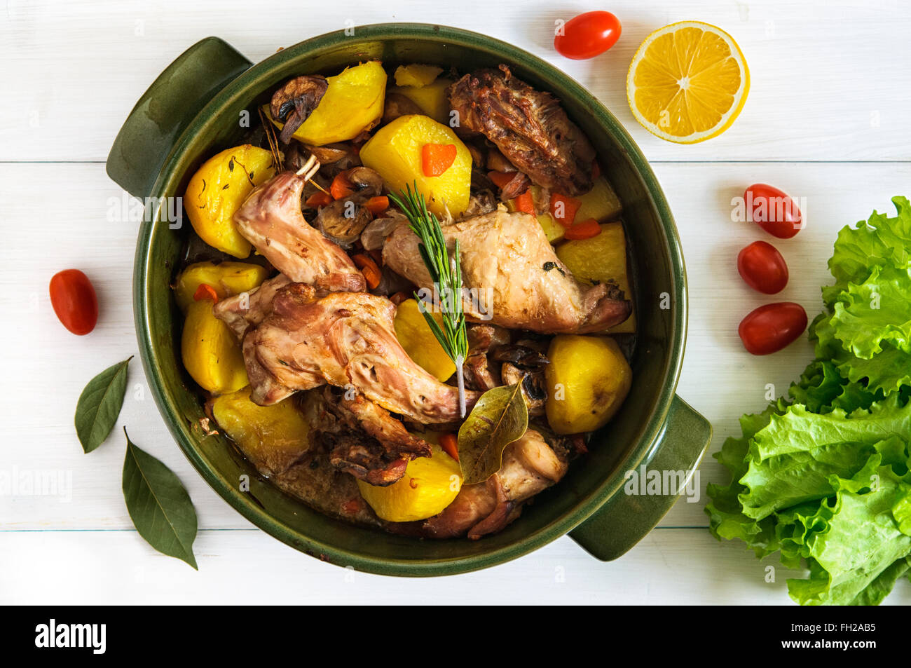 Top flat view of roasted rabbit meat with vegetables in round ceramic ...