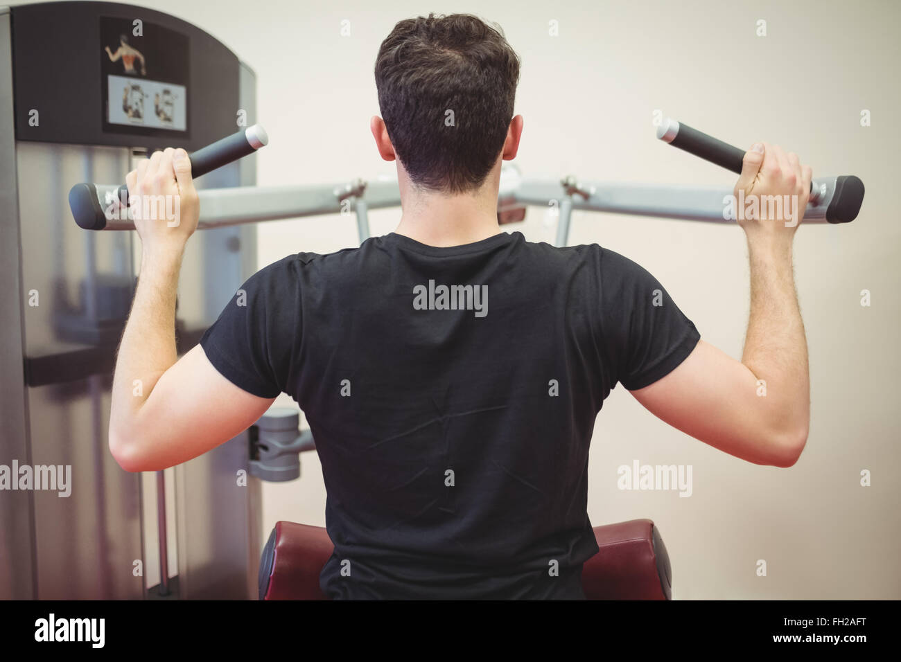 Fit man using weights machine for arms Stock Photo - Alamy