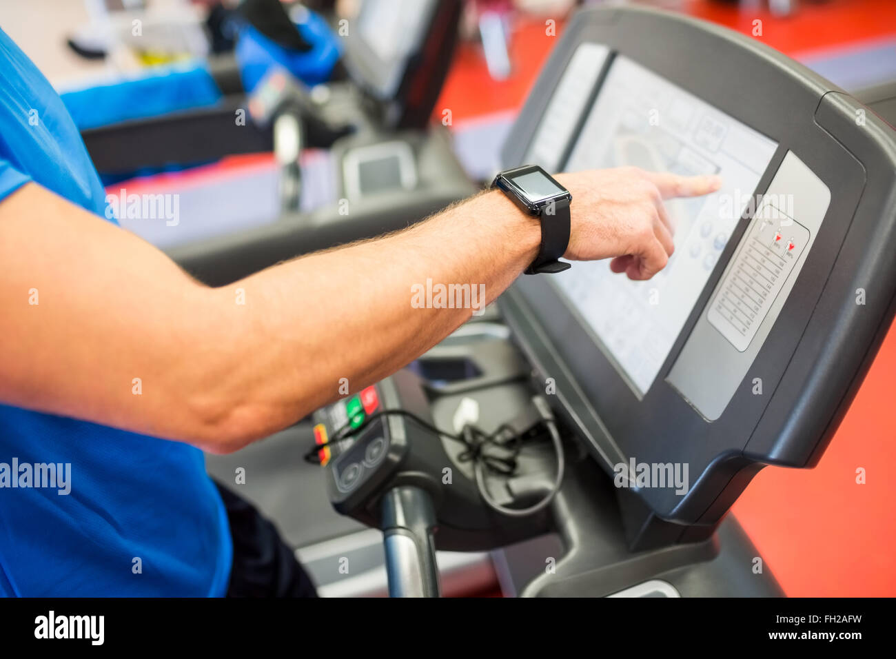 Man adjusting the settings of a treadmill Stock Photo - Alamy