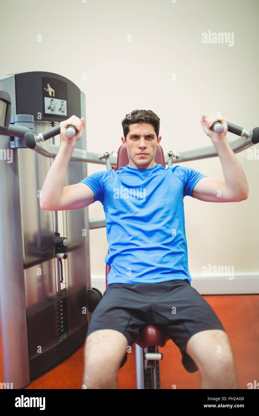 Fit man using weights machine for arms Stock Photo - Alamy