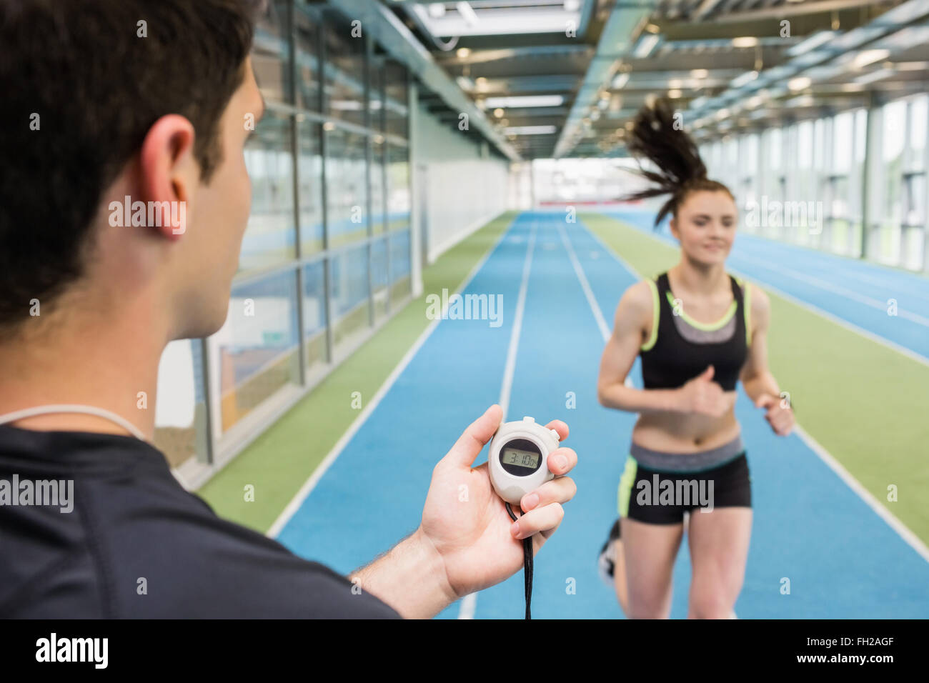 Trainer timing woman on the track Stock Photo - Alamy