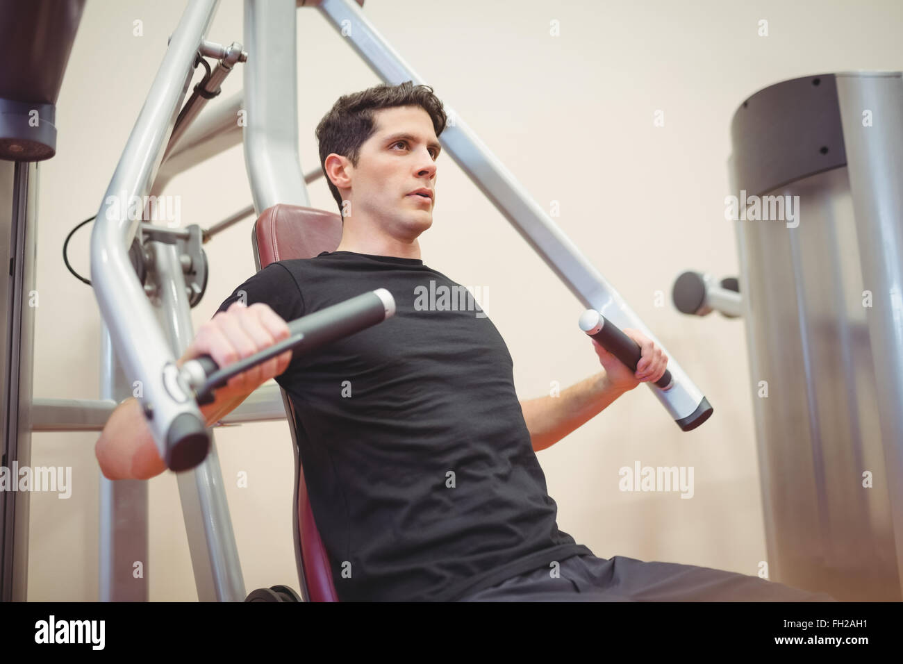 Fit man using weights machine for arms Stock Photo - Alamy