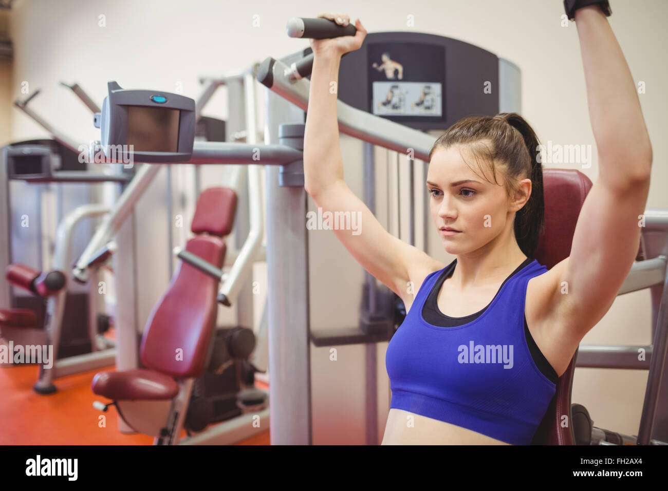 Fit woman using weights machine for arms Stock Photo - Alamy