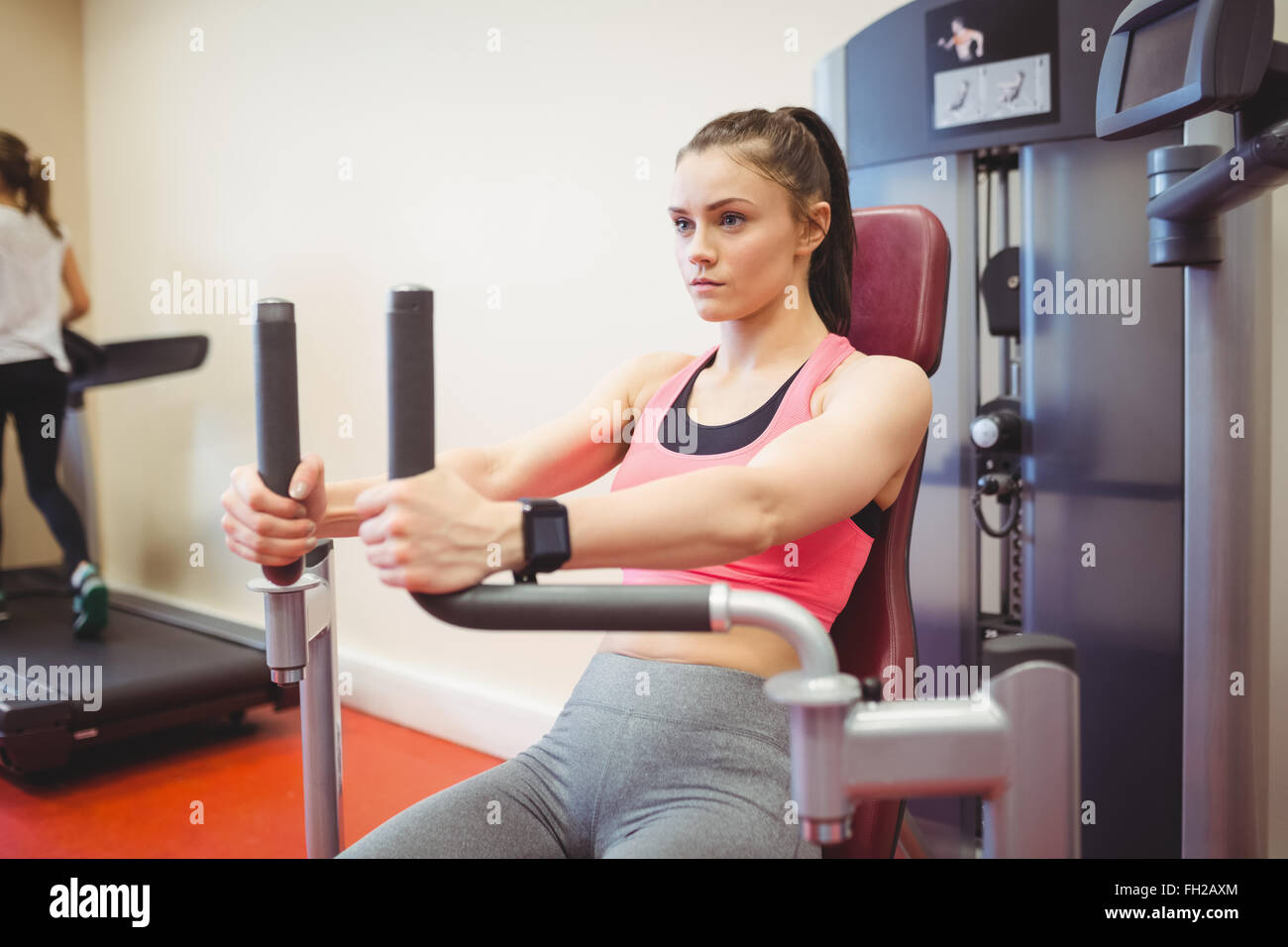 Fit woman using weights machine for arms Stock Photo - Alamy