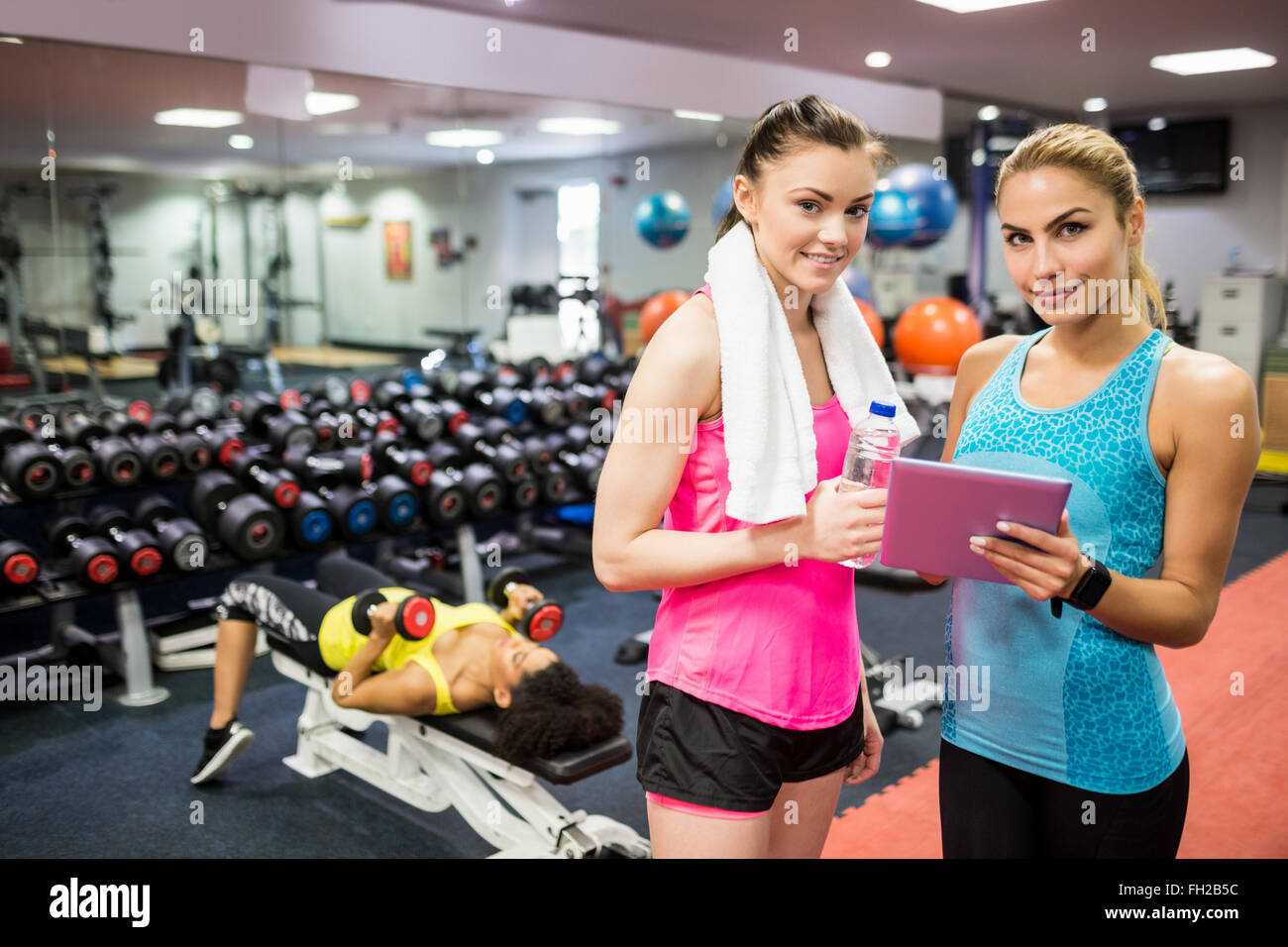 Fit women using tablet in weights room Stock Photo - Alamy