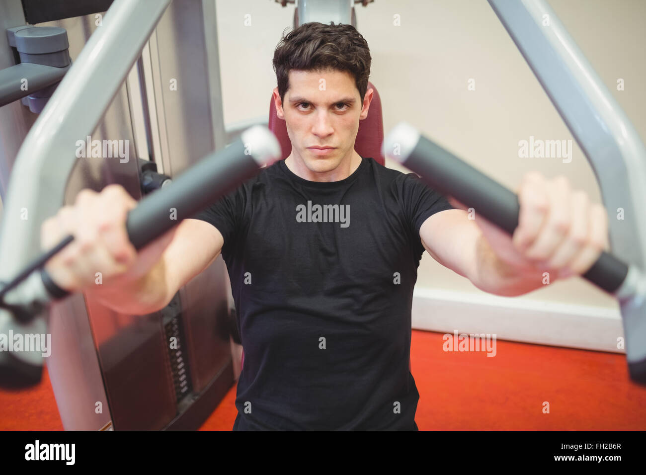 Fit man using weights machine for arms Stock Photo - Alamy