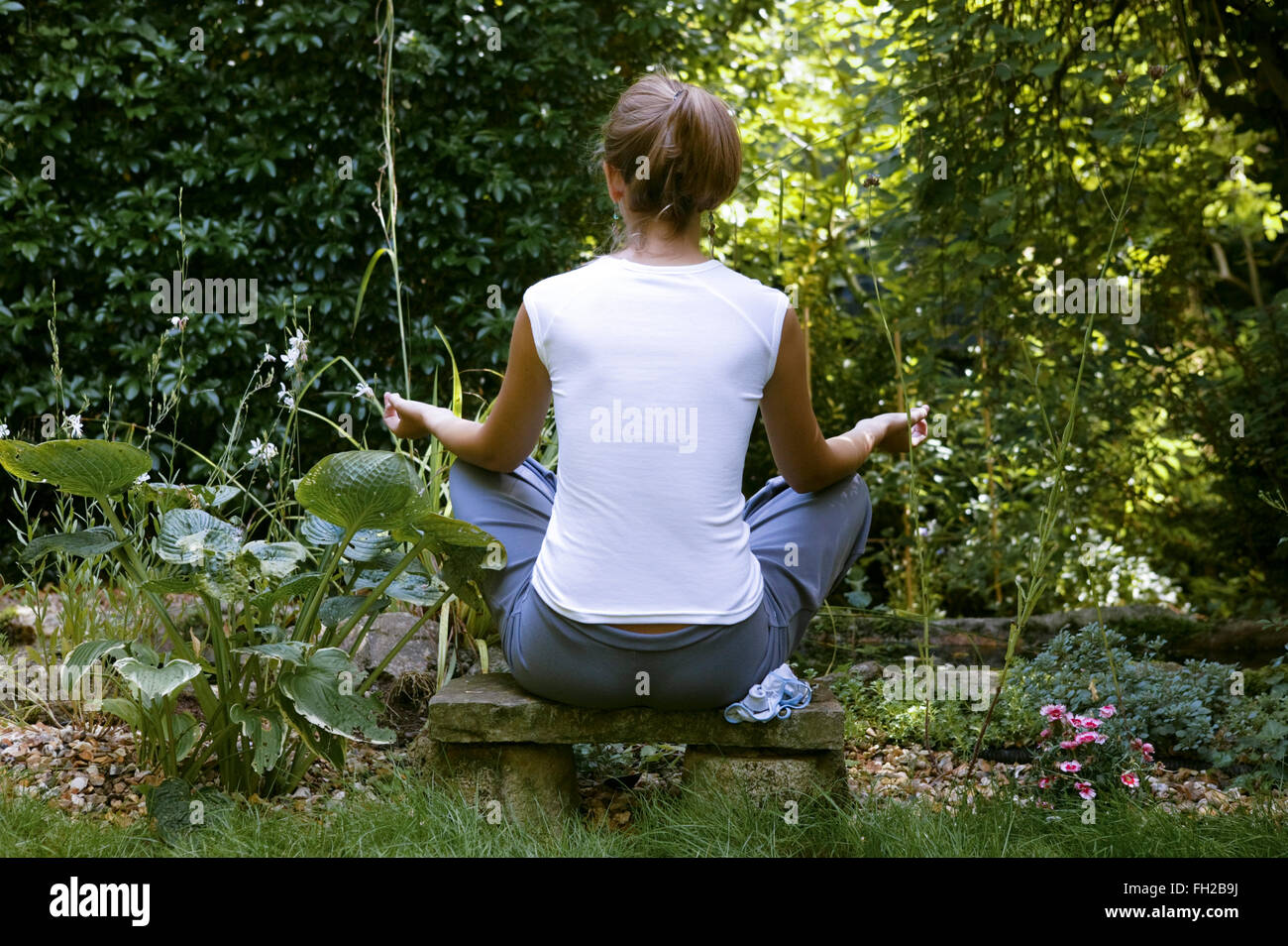 A young woman sitting quietly at a retreat and meditating in a peaceful ...
