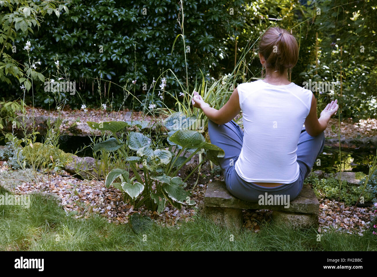 A young woman sitting quietly at a retreat and meditating in a peaceful ...
