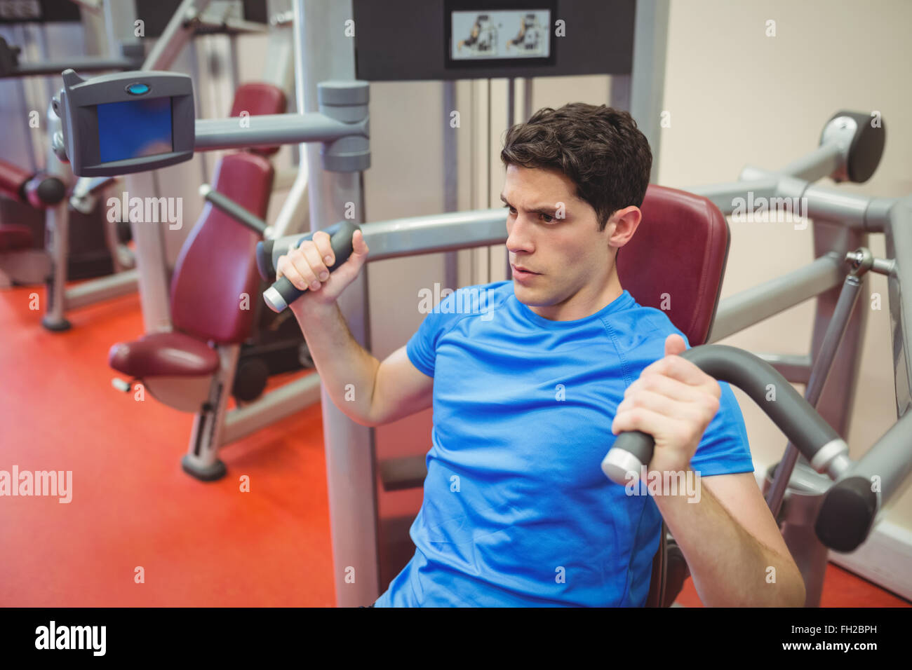 Fit man using weights machine for arms Stock Photo - Alamy