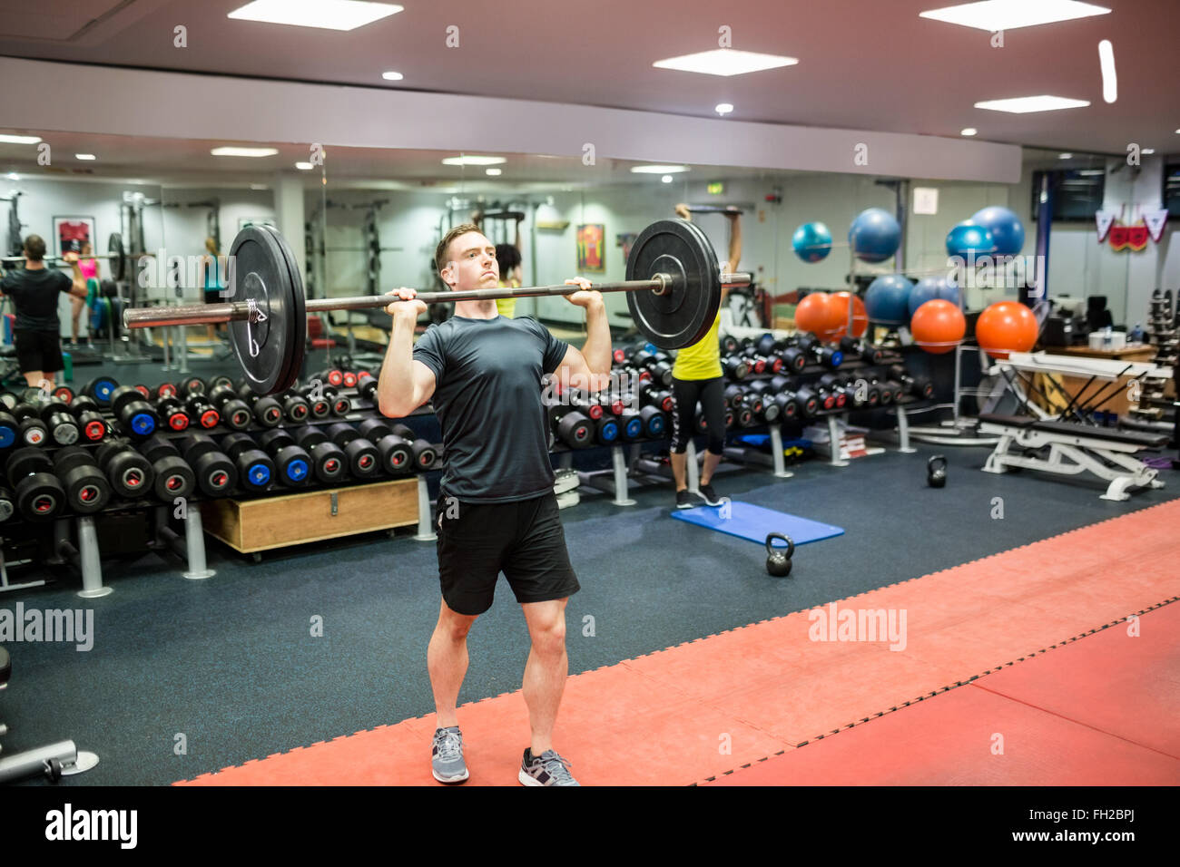 Fit man lifting heavy barbell in weights room Stock Photo - Alamy