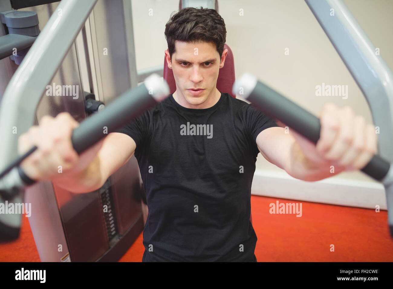 Fit man using weights machine for arms Stock Photo - Alamy