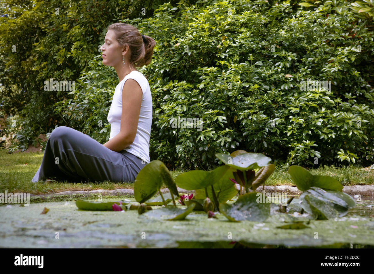 A young woman sitting quietly at a retreat and meditating in a peaceful ...