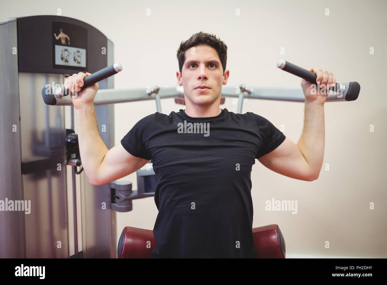 Fit man using weights machine for arms Stock Photo - Alamy