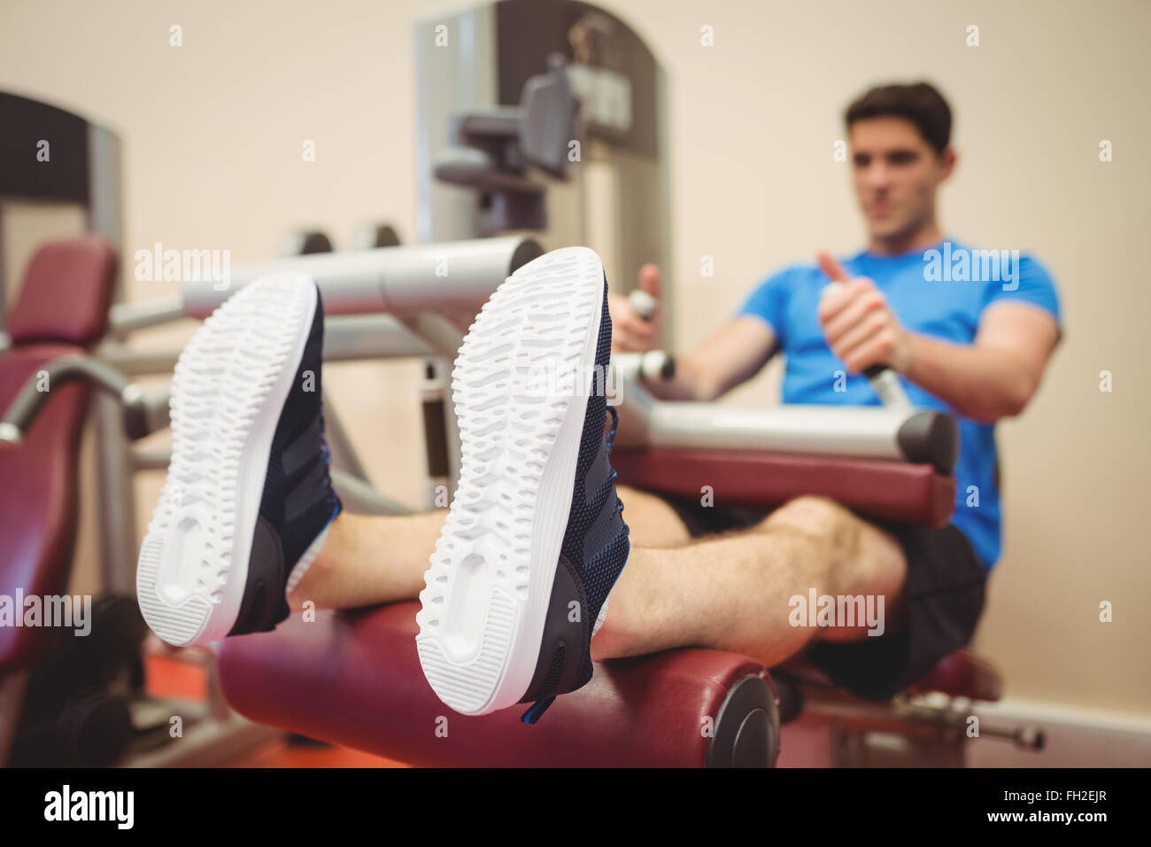 Fit man using weights machine for legs Stock Photo - Alamy