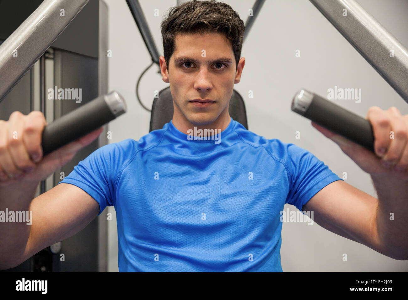 Focused man using the weights machine Stock Photo - Alamy