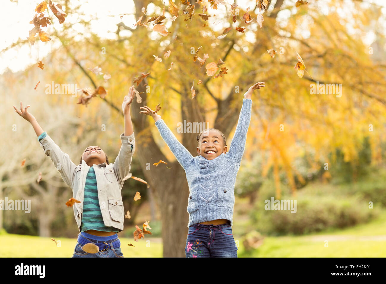 Portrait of young children throwing leaves around Stock Photo - Alamy