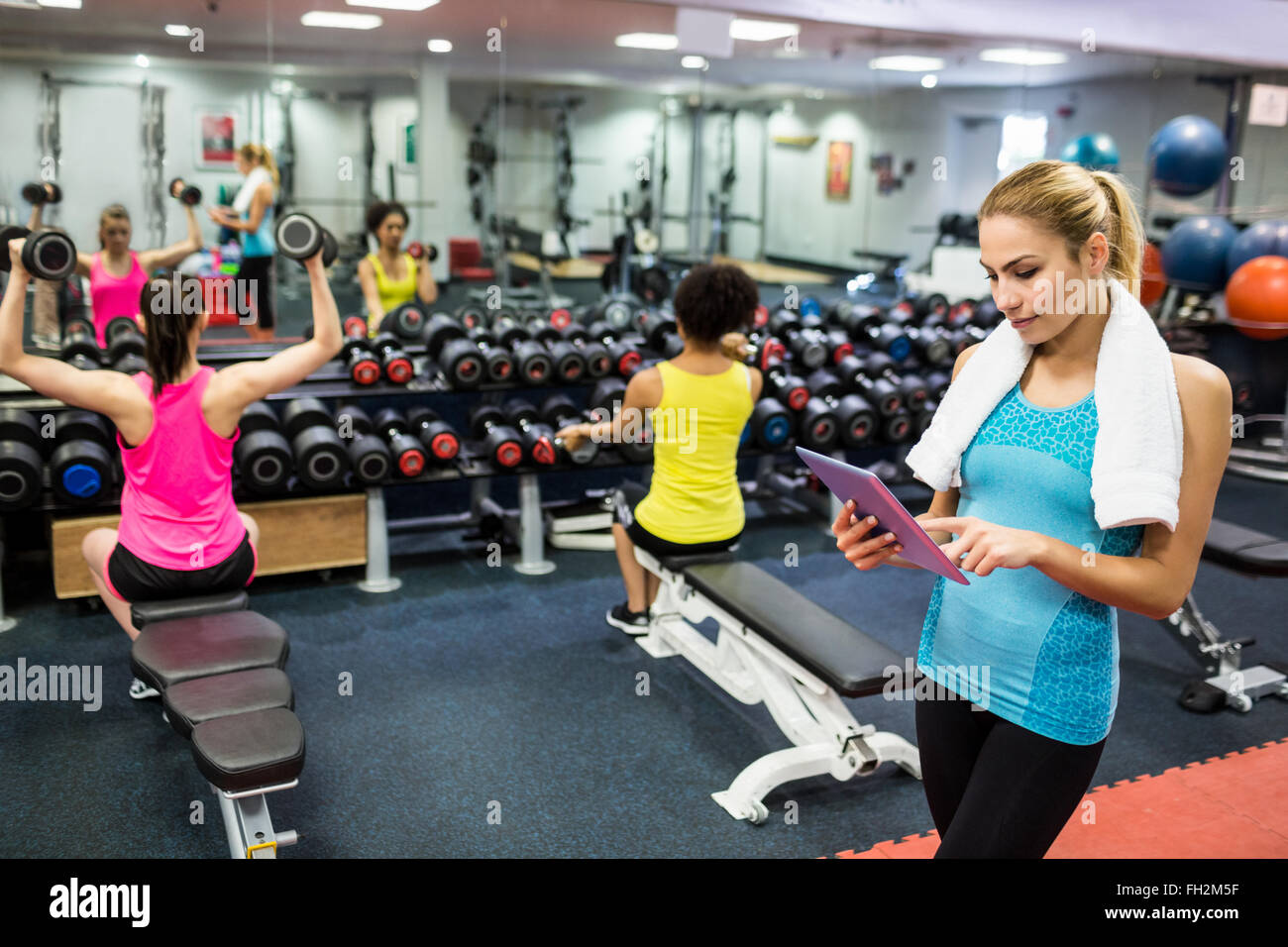 Fit woman using tablet in weights room Stock Photo - Alamy