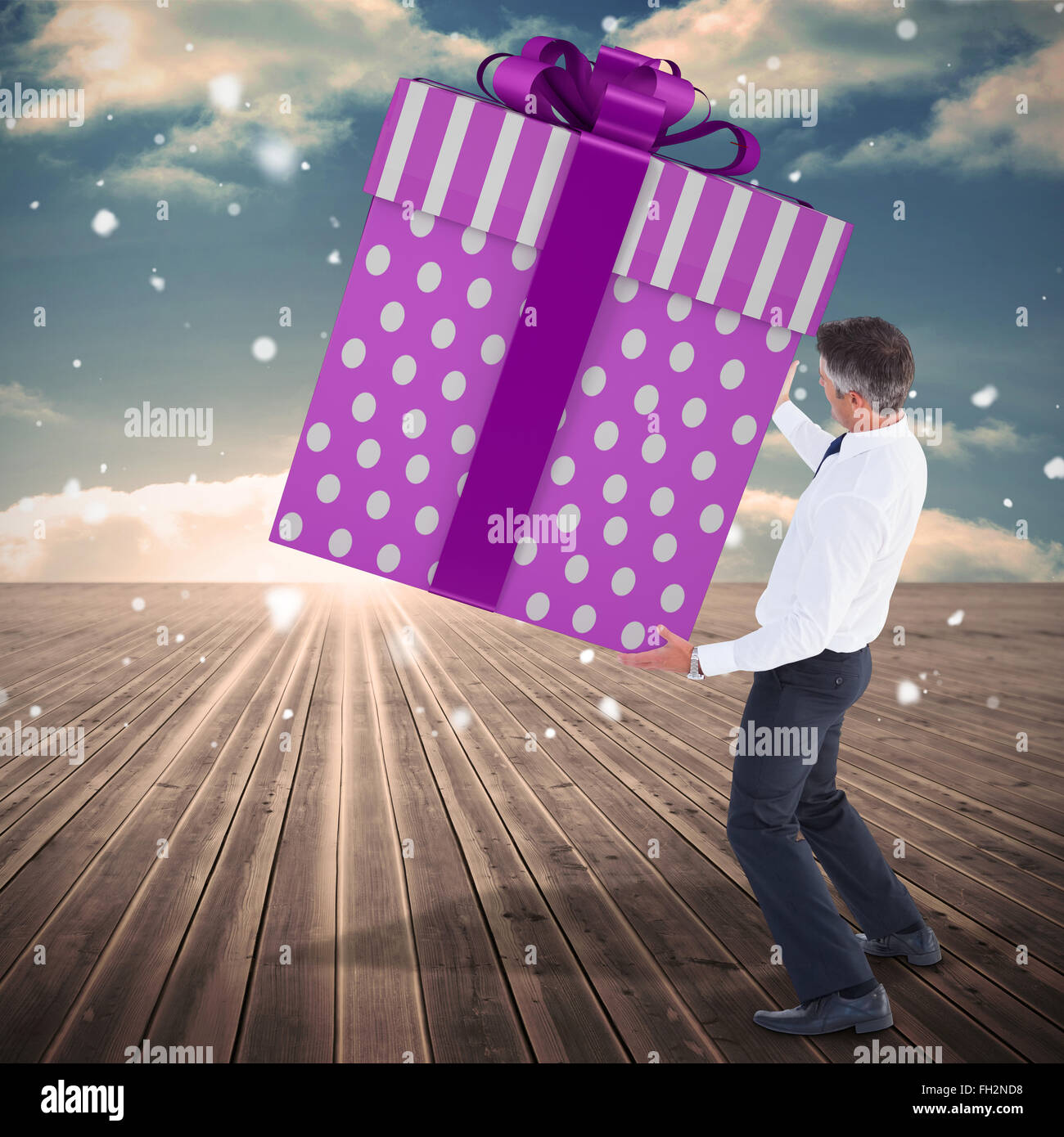Composite image of stylish man with giant gift Stock Photo - Alamy