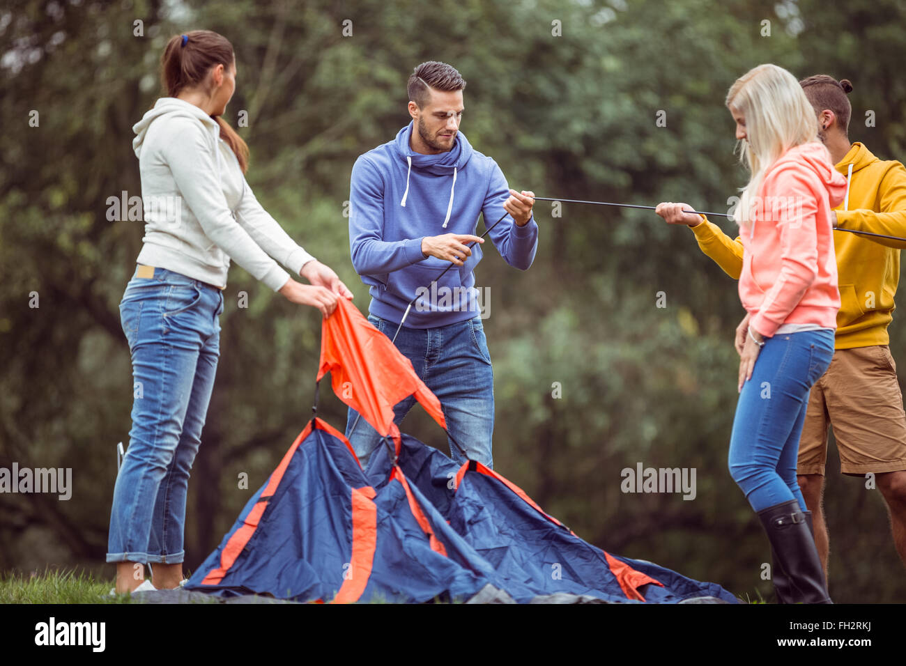 Happy friends setting up their tent Stock Photo - Alamy