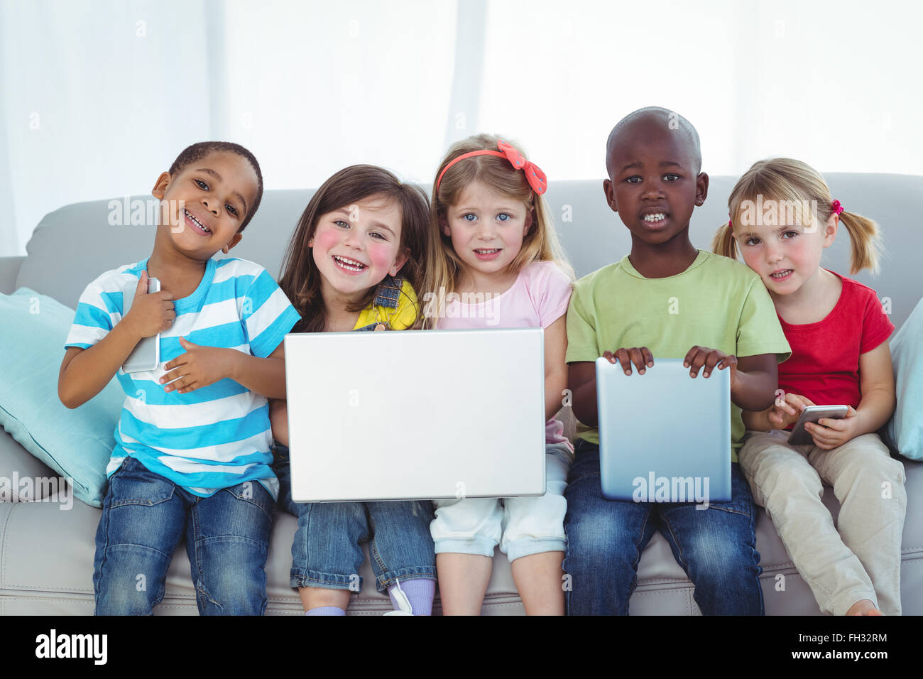 Happy kids using technology while sitting Stock Photo - Alamy