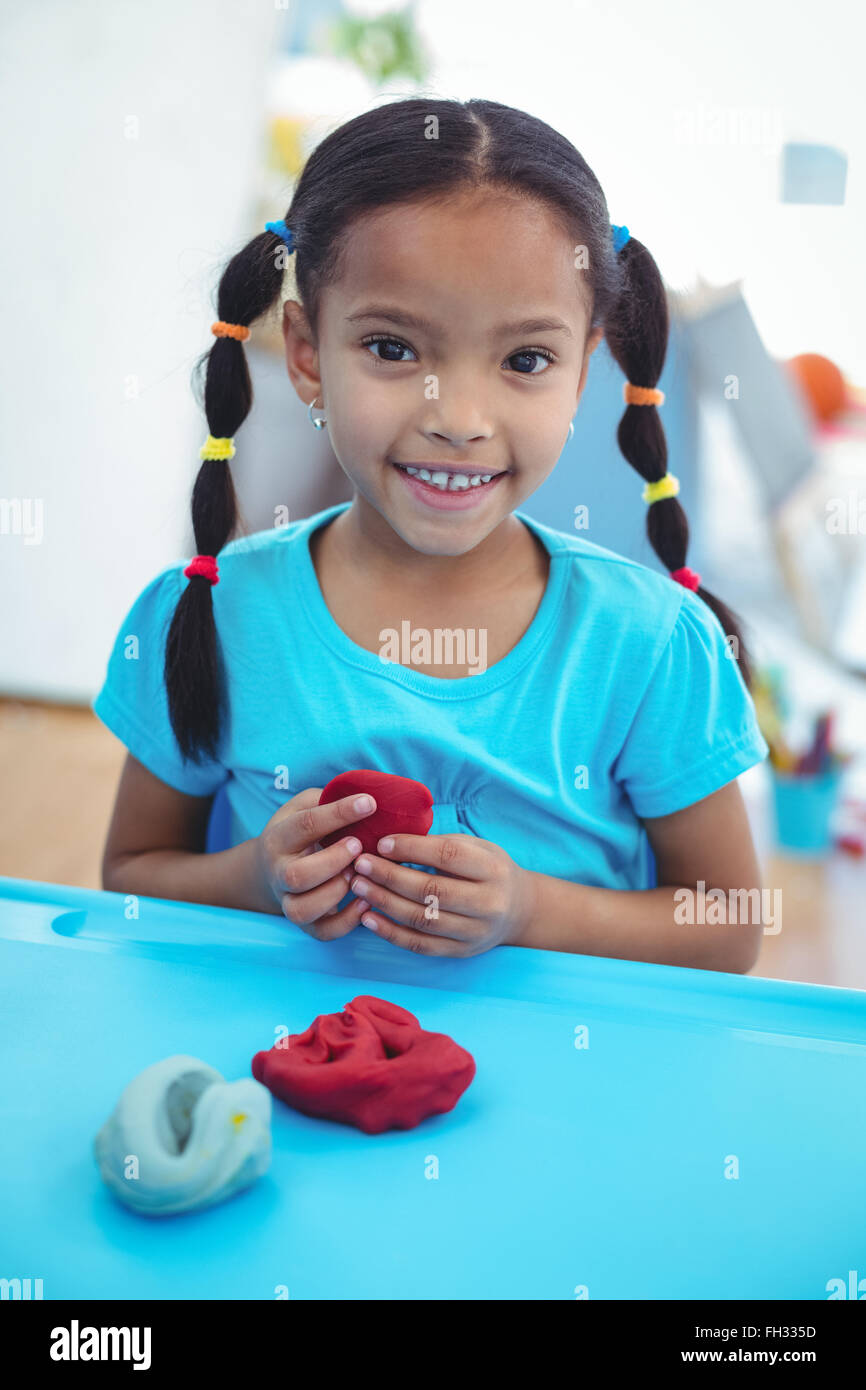 Smiling girl using modelling clay Stock Photo - Alamy