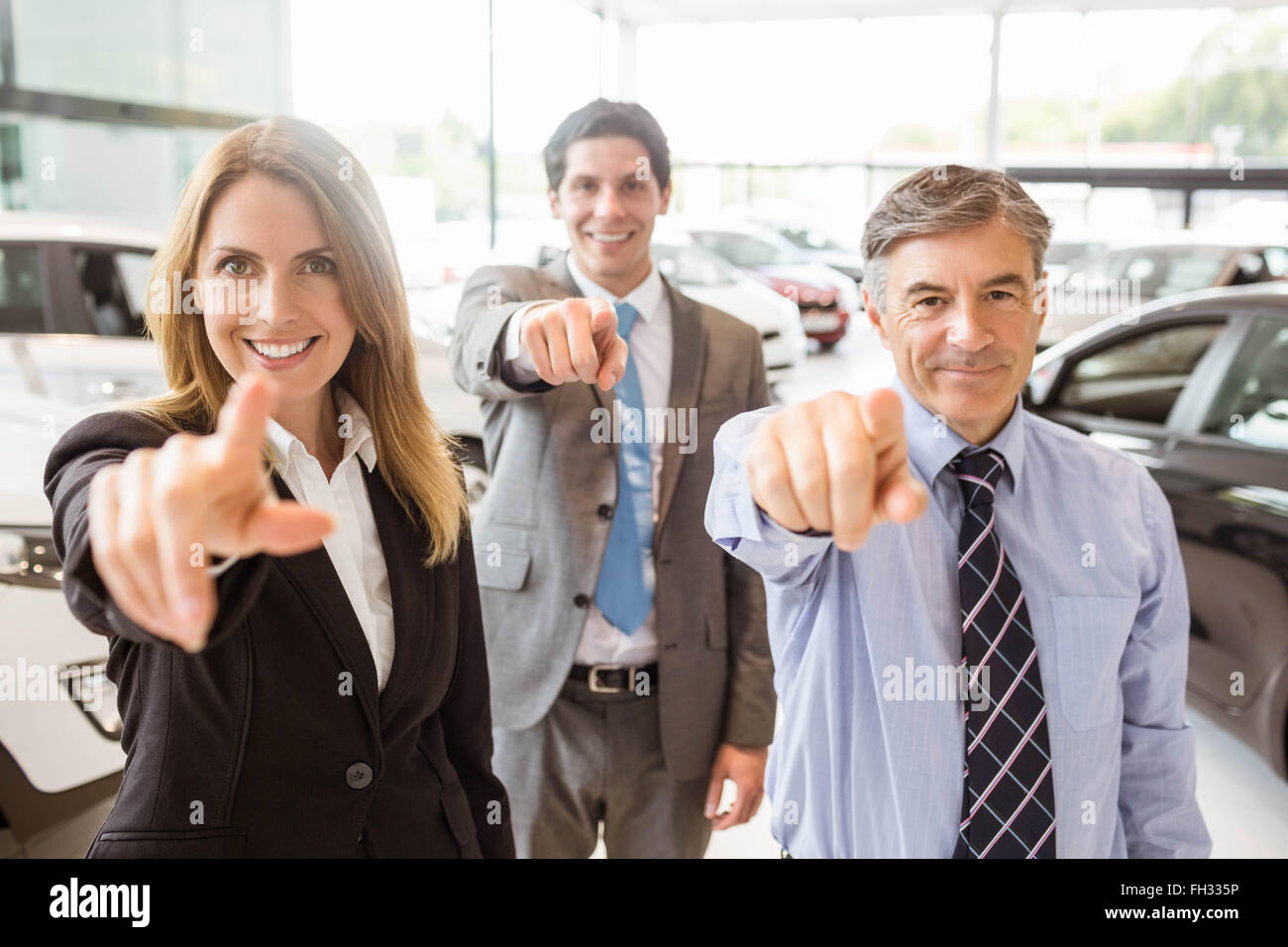 Group of smiling business team pointing together Stock Photo - Alamy