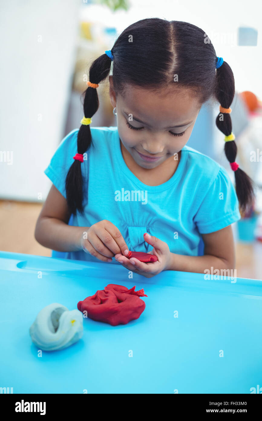 Smiling girl using modelling clay Stock Photo - Alamy