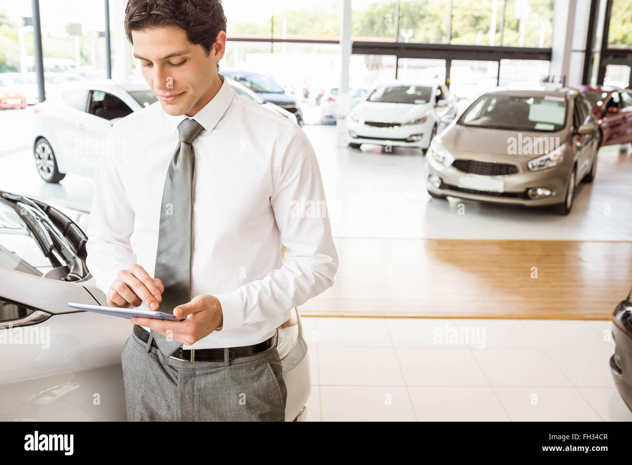 Smiling salesman using tablet near a car Stock Photo - Alamy