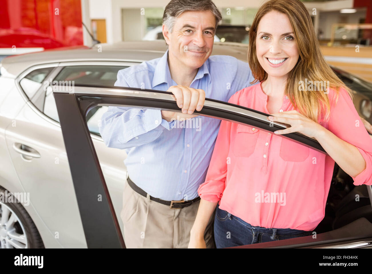 Smiling couple leaning on car Stock Photo - Alamy