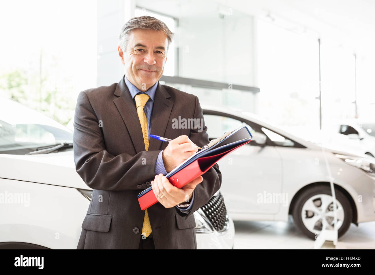 Smiling salesman writing on workbooks Stock Photo - Alamy