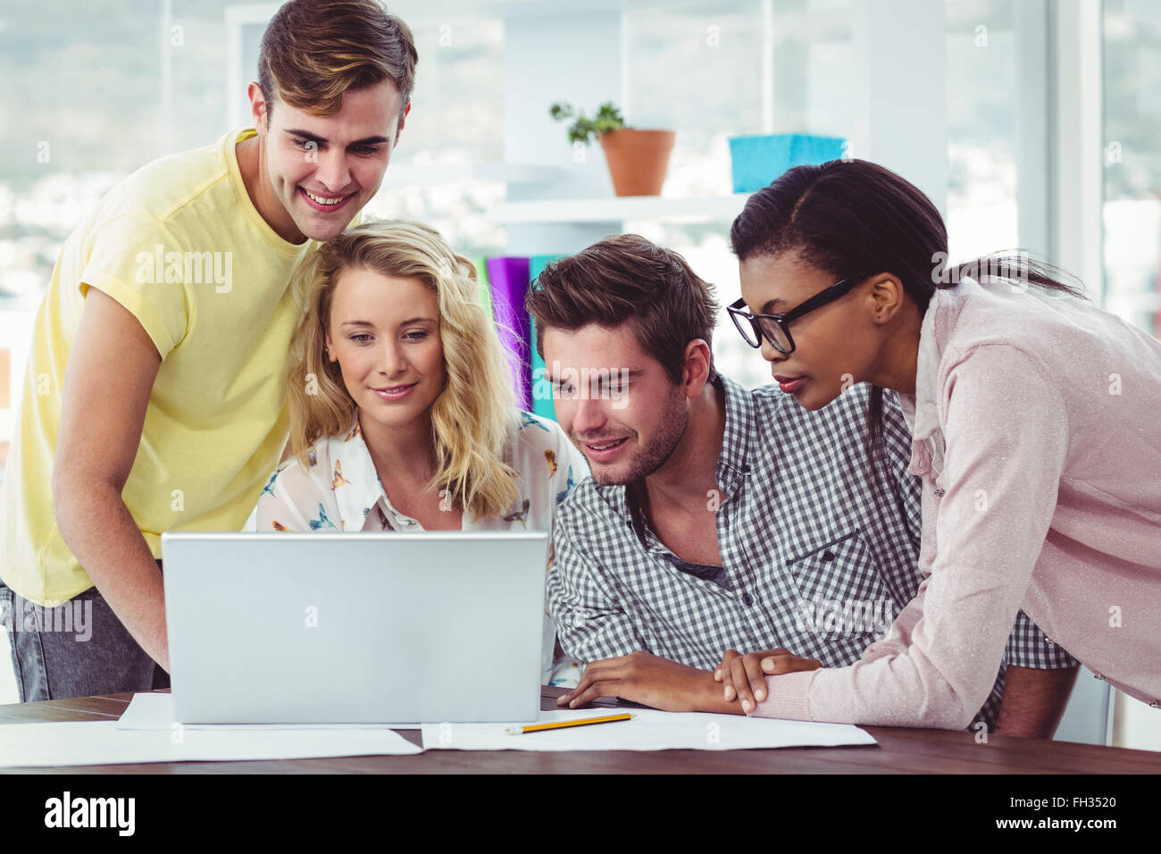 Creative business team working on a laptop together Stock Photo - Alamy